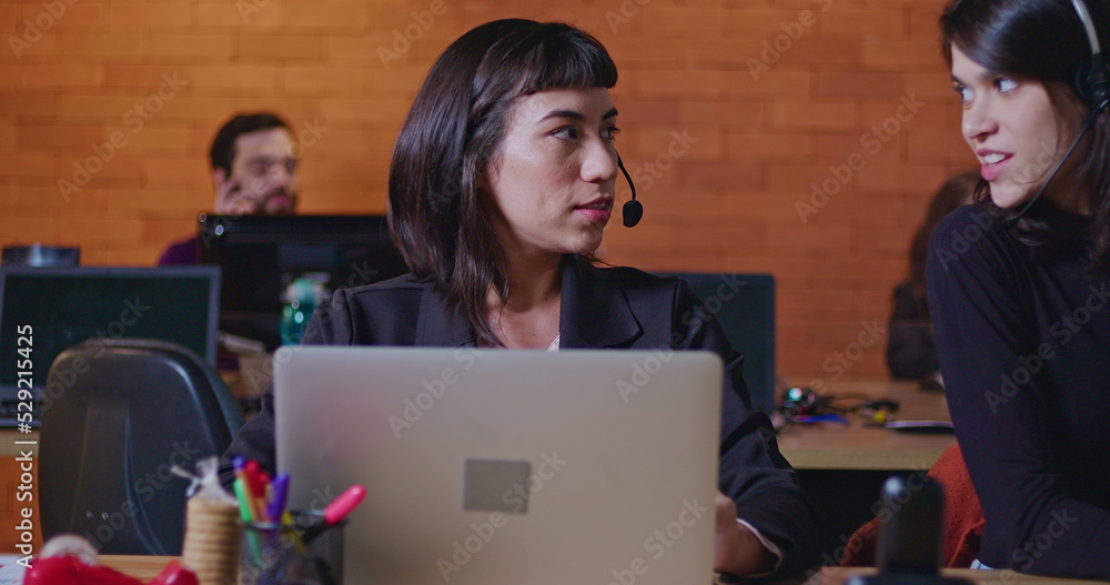Female employee speaking with colleague at call center giving feedback ...