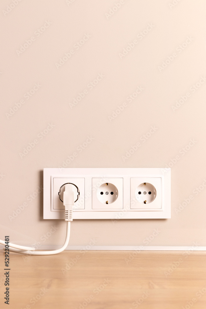 Group of white european electrical outlets with plug inserted into it ...