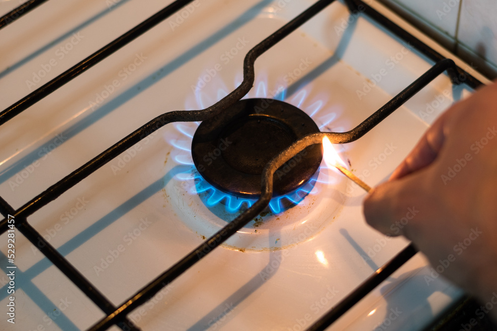 hombre encendiendo con un fosforo una hornalla de una cocina blanca ...