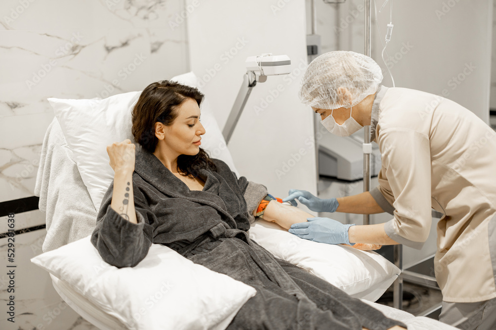 Nurse makes an injection into a vein taking blood for tests or washing ...