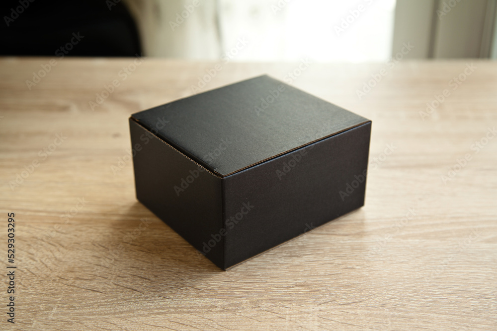 Closed rectangular cardboard box with corrugated cardboard lid, on oak ...