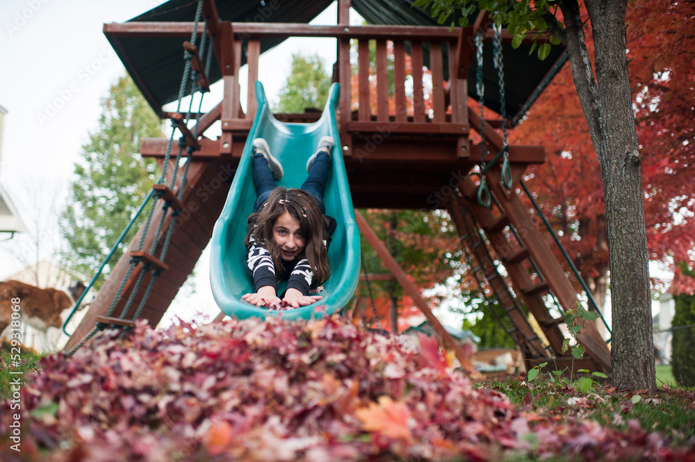 Cute girl slides down slide head first into a pile of leaves Stock ...