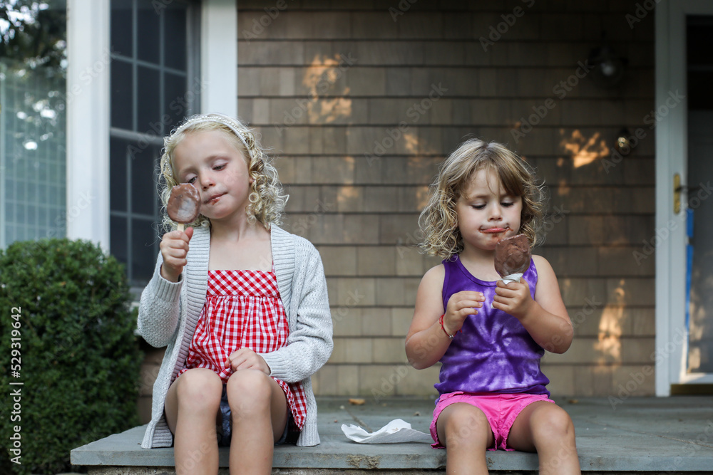Foto de two girls sitting on porch steps eating ice pops in summer do ...