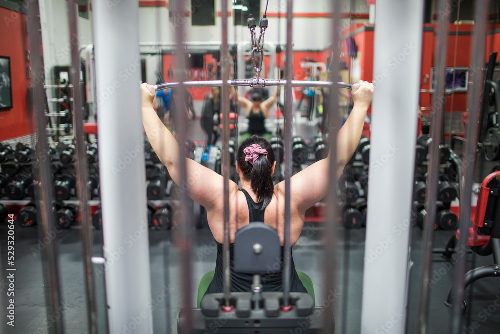 Strong woman completes shoulder pull-down at the gym. Stock Photo ...
