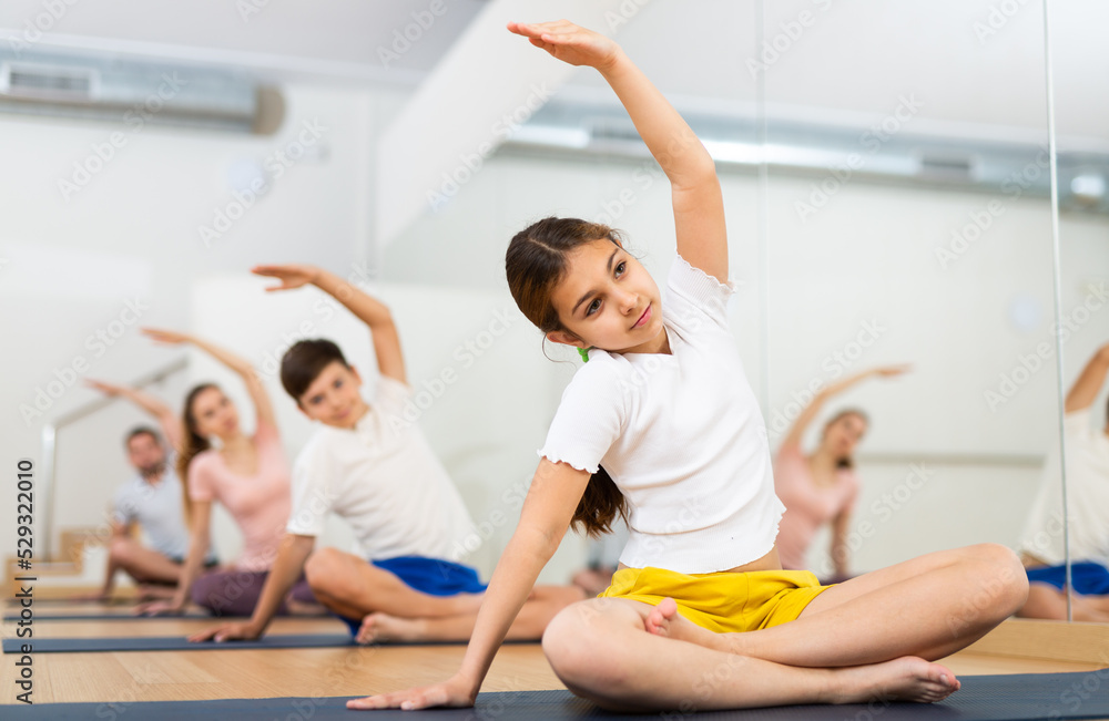 Cute tween girl with brother and parents exercising Hatha yoga in ...