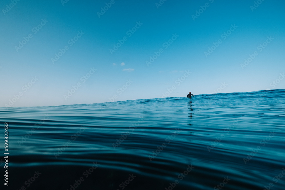 Pulled-back view of a surfer waiting for a wave on his surfboard Stock ...