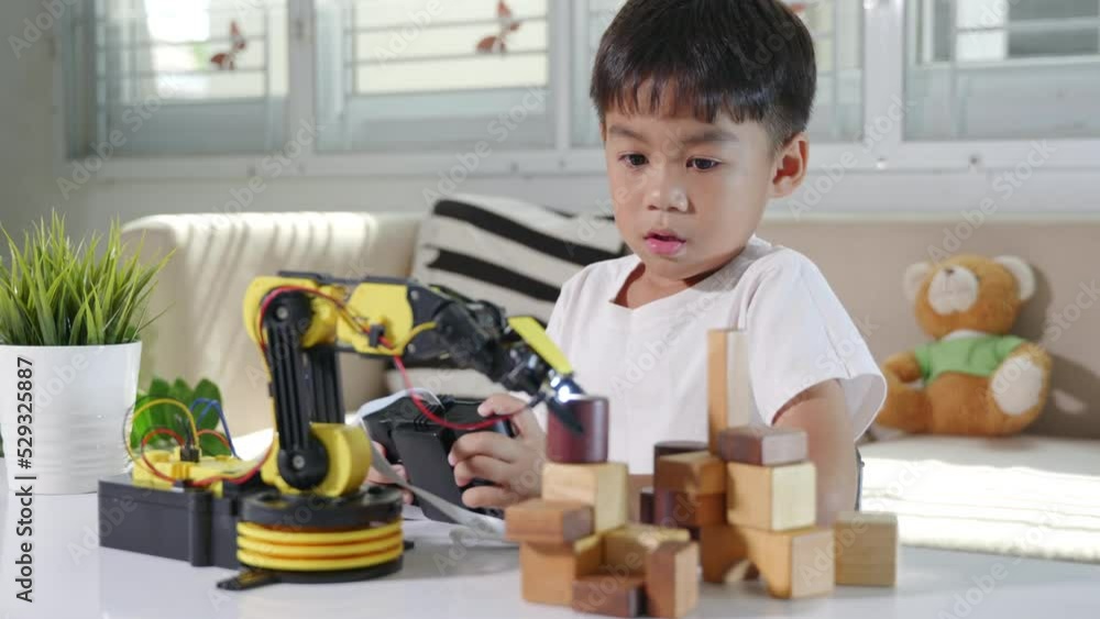 Happy Asian little kid boy using remote control playing robotic machine ...