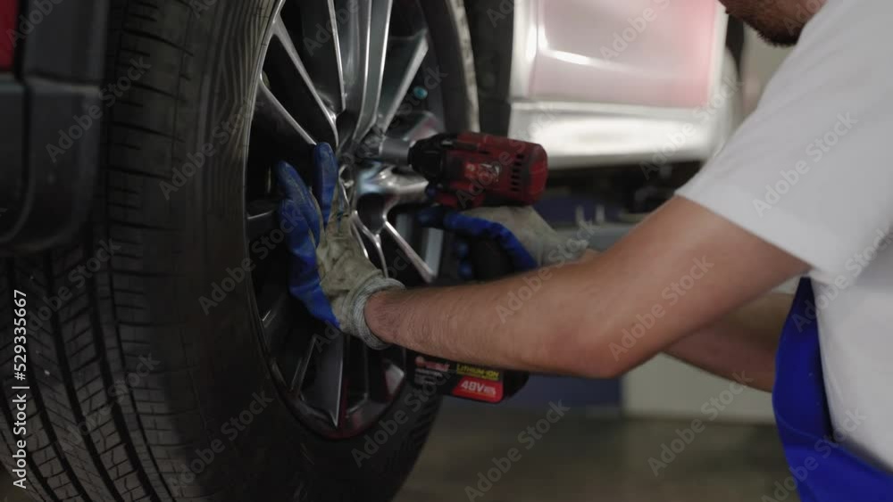 auto mechanic is putting wheels on a car in a garage. Concept of safety ...