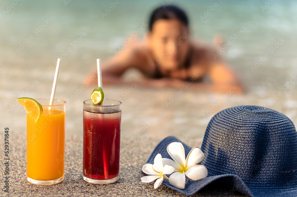 Closeup cocktails on beach with blurred tourist woman lying on ...