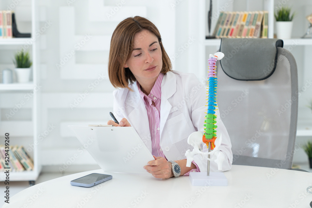 Young attractive female doctor orthopedist demonstrating the problem on ...