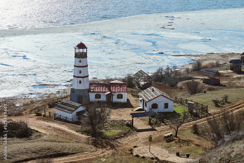 Beautiful white red lighthouse with farm utility houses in Merzhanovo ...