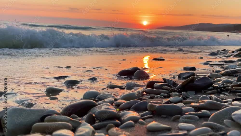 Beautiful sunset on the seashore on a bright sunny day. The waves break ...