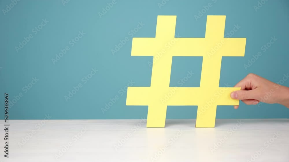 Close up of female hands hold large yellow paper hashtag symbol at ...