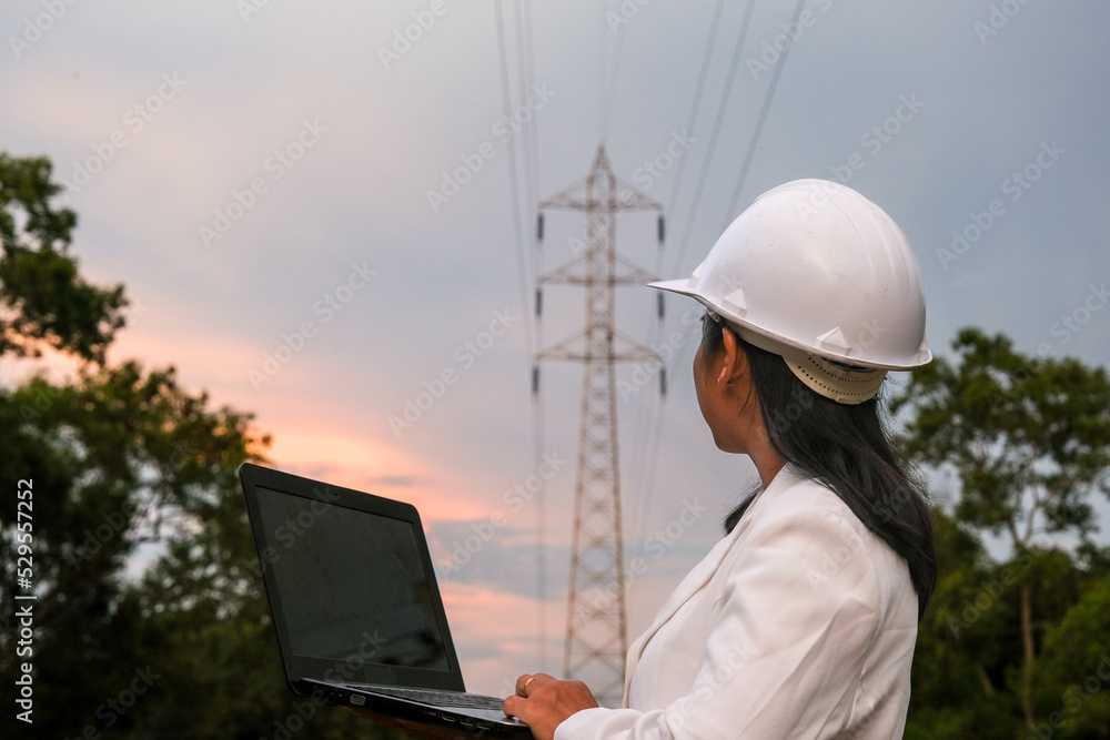 Asian female electrical engineer working on laptop near high voltage ...