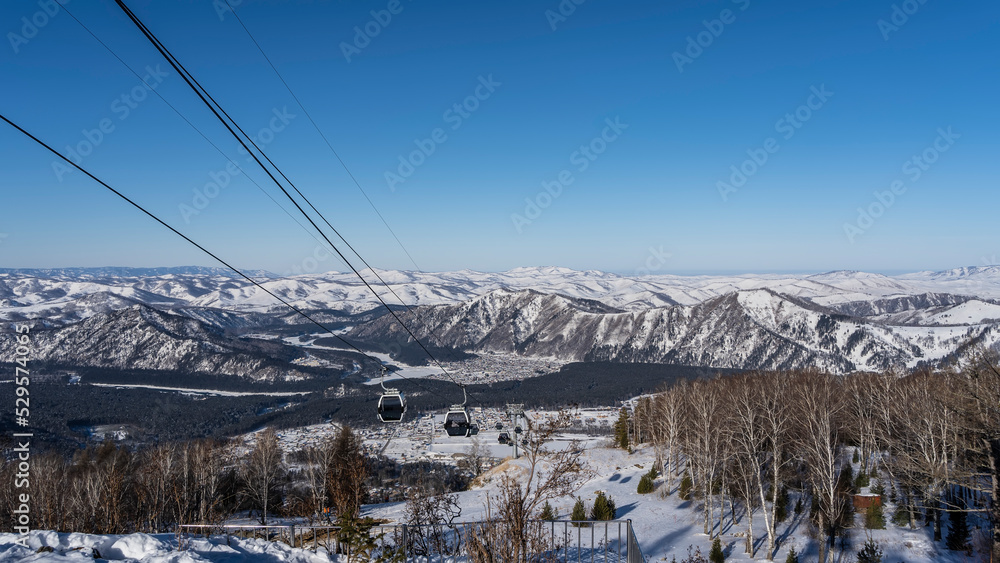 The ropes of the cable car pass over a snow-covered high-altitude ...