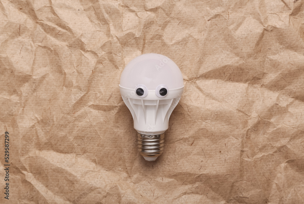 Light bulb with eyes on craft crumpled paper background. Eco concept ...