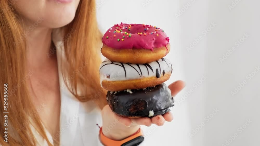 Unhealthy eating concept. Young woman smells with pleasure tasty donuts ...