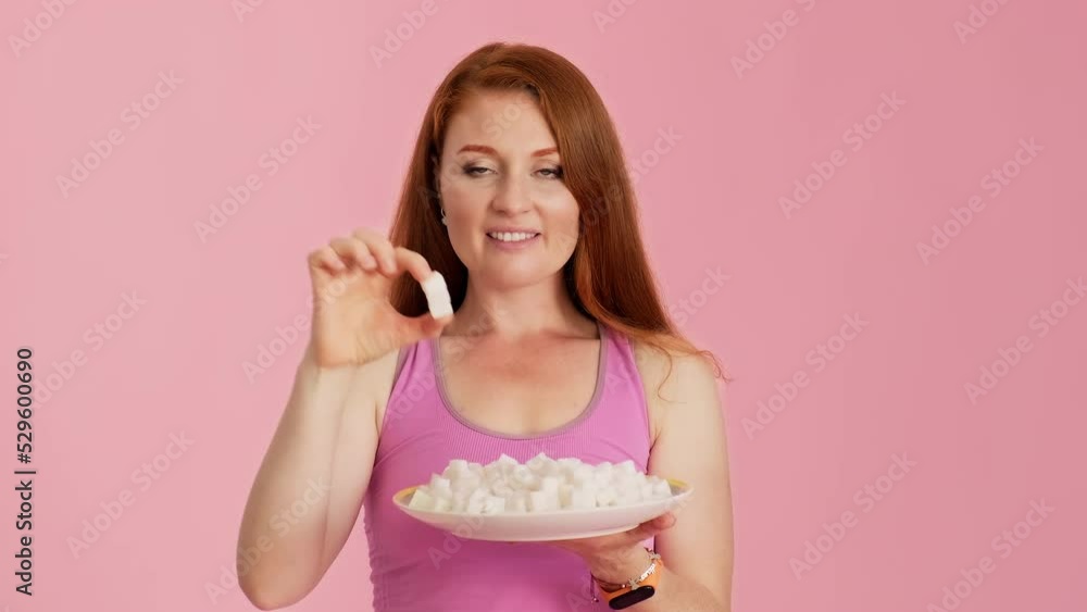 Woman is holding plate of sugar cubes at pink background. Unhealthy ...