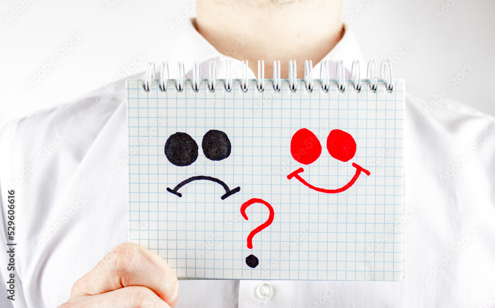 Cheerful and sad emoticon.Man holding a notepad with a sad and smiling ...