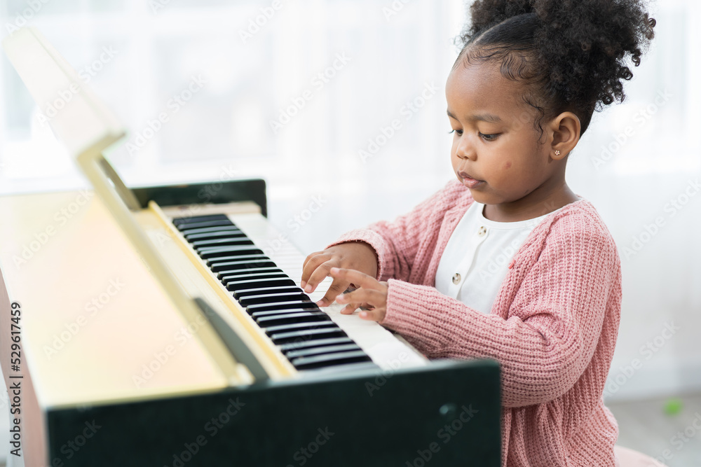 Child girl playing piano at home. African American little girl practice ...