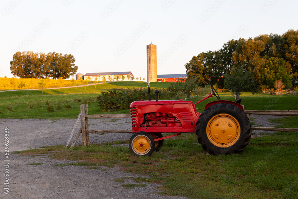 Old red tractor in farm land with rural buildings in soft focus ...