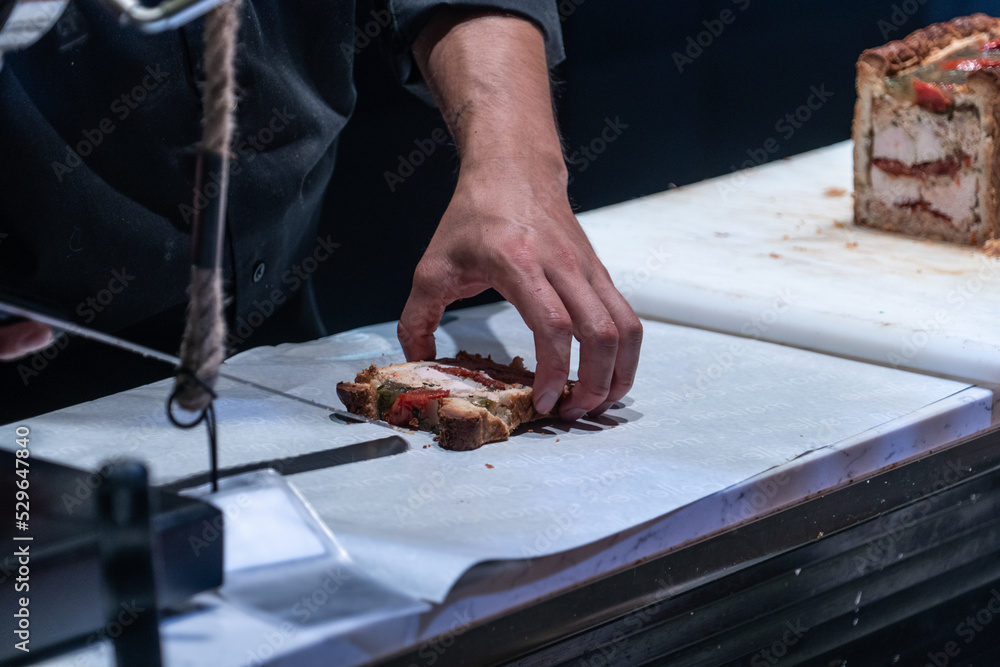 Male hand wrapping on a paper a pate en croute an appetizer meat pie ...