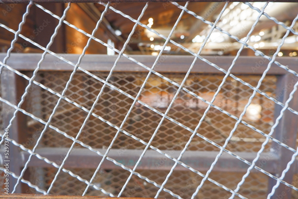 Rectangular steel mesh, placed as a barrier, with a steel background ...