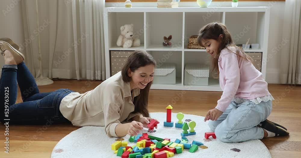 Happy engaged mom and cheerful daughter girl playing on heating floor ...