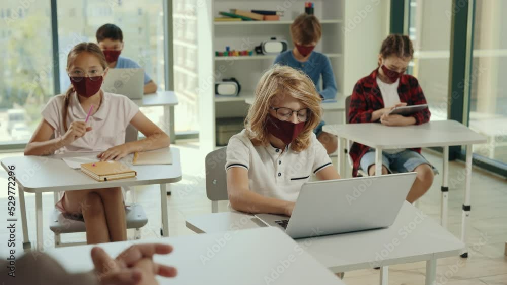 Pupils doing their task using the laptop wearing masks in a class ...