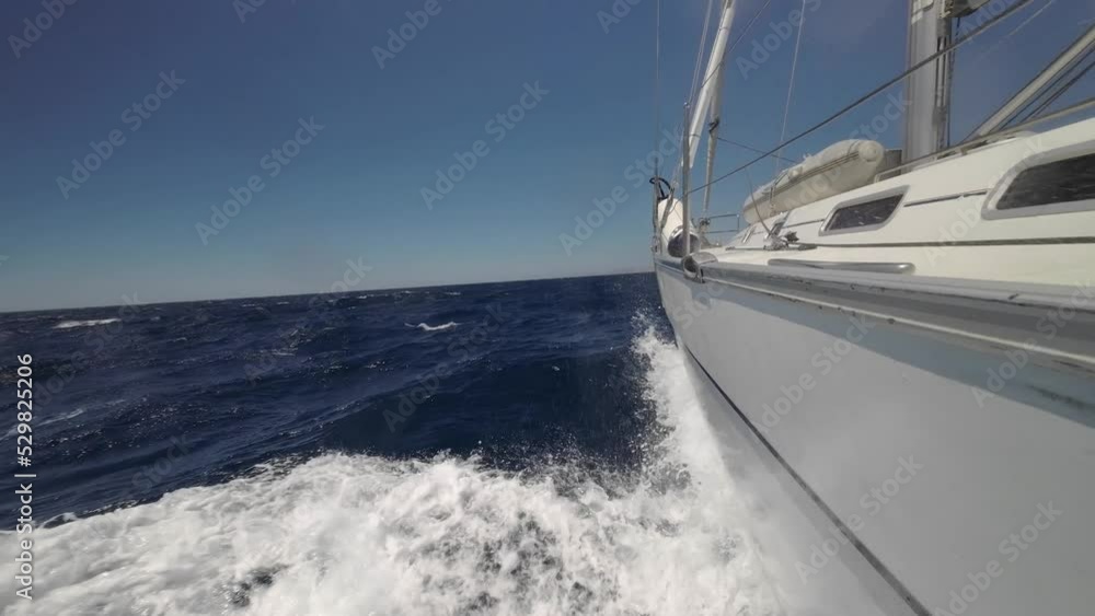 Floating sailing yacht with spread sails splitting the sea waves and an ...