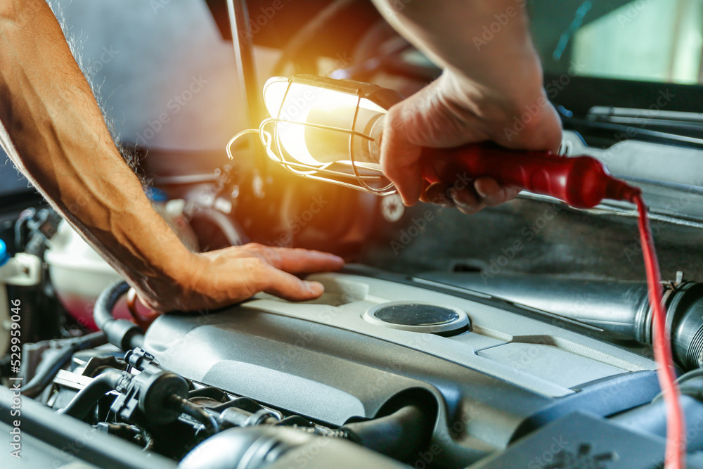 mechanic examines the car engine. checking the health of the car engine ...