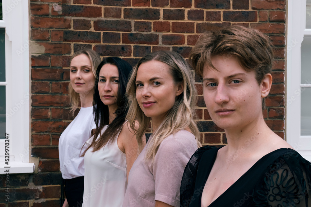 Non-binary person with friends standing together in front of wall Stock ...