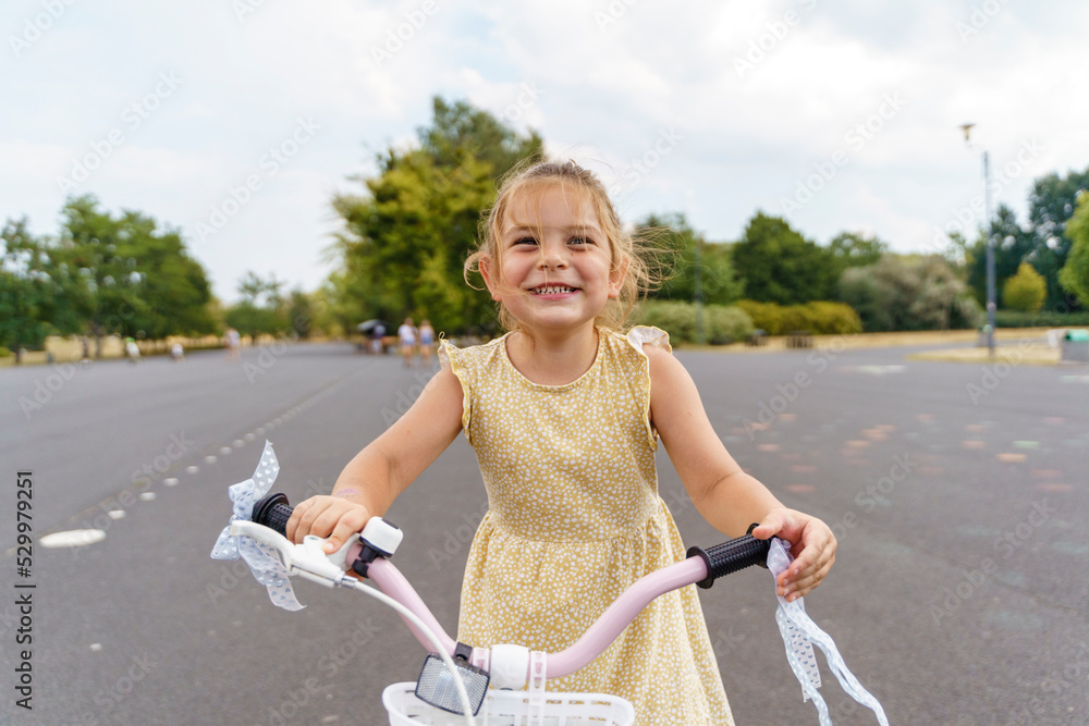 Happy girl sitting on bicycle at park Stock Photo | Adobe Stock