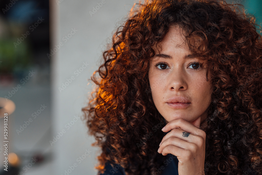 Curly haired beautiful young woman with hand on chin Stock Photo ...