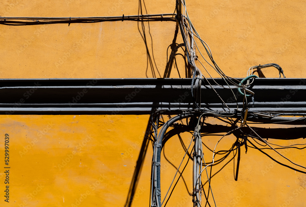 Yellow wall facade with wires, cabling and electric installations for ...