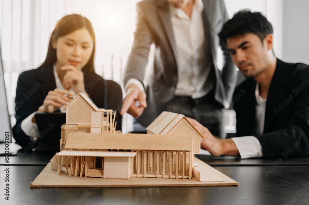 Shot of scale model house on table with architects. Two architects ...