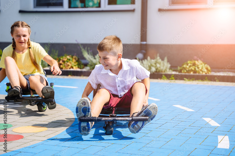 Two children, boy and girl, compete ride mini bikes on the playground ...