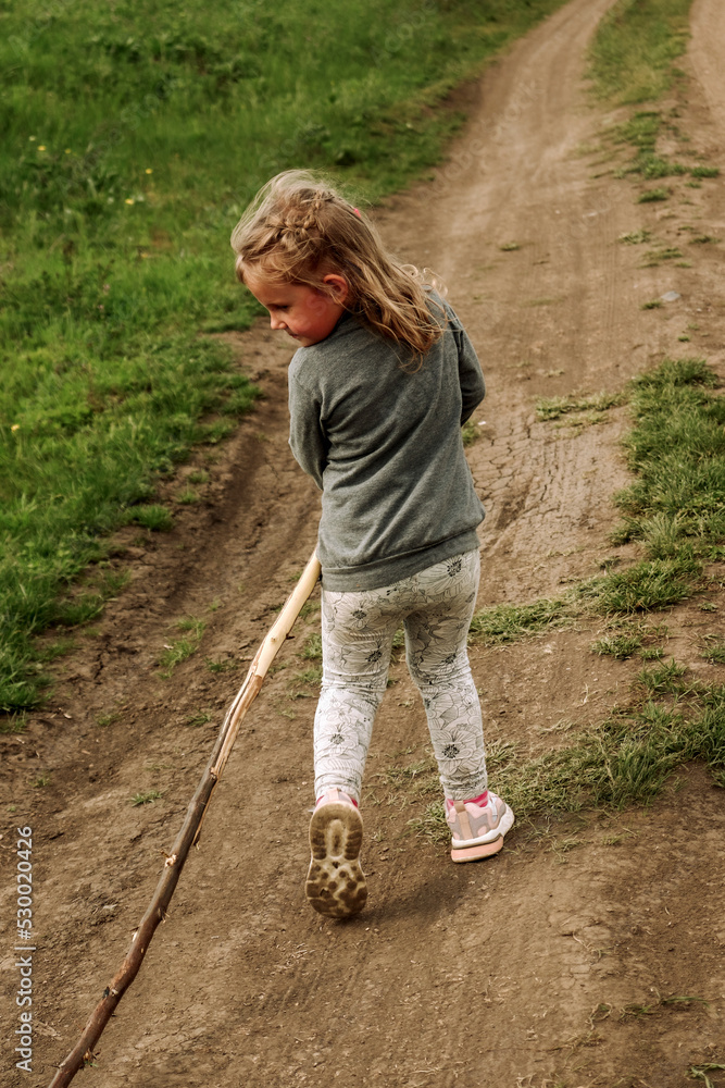 The child plays with a tree stick. Children's portrait. Blonde Girl 4 ...
