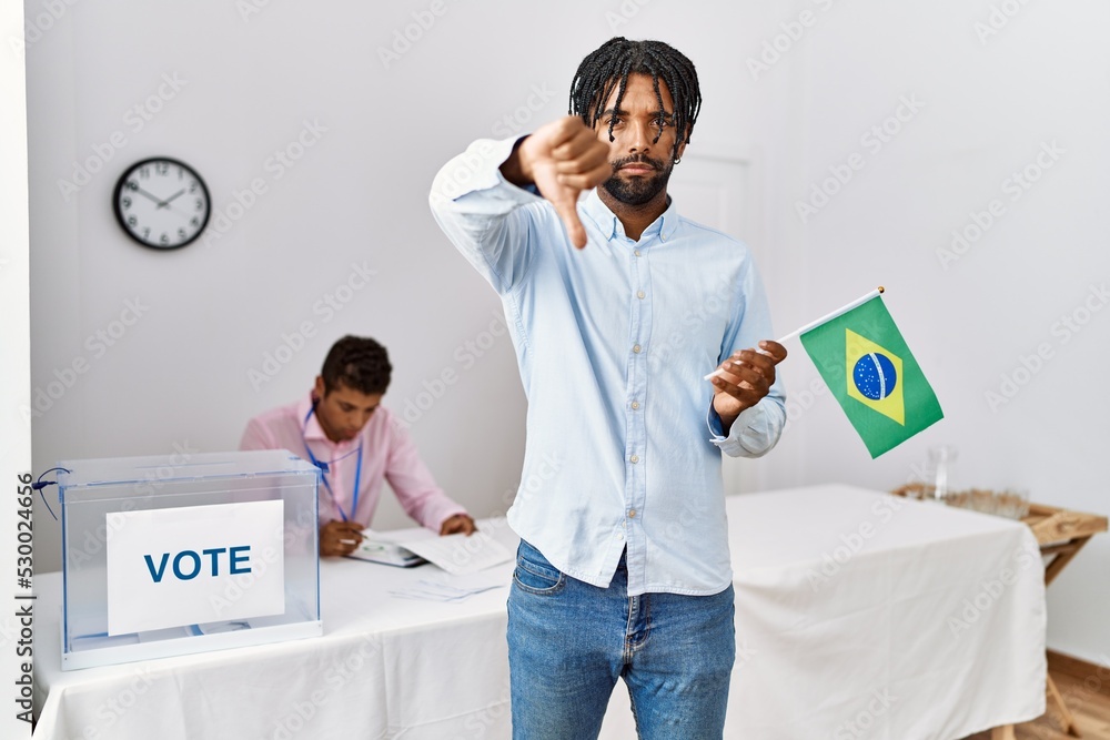 Young hispanic men at political campaign election holding brazil flag ...