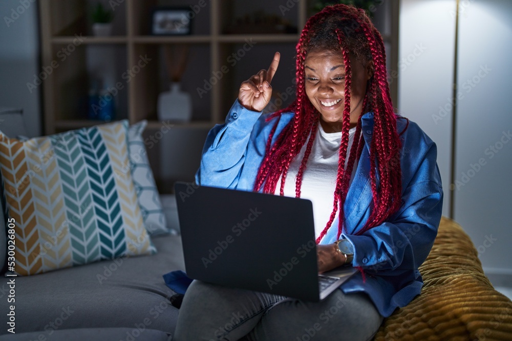 African american woman with braided hair using computer laptop at night ...