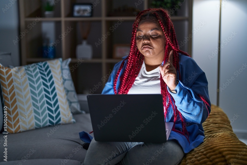 African american woman with braided hair using computer laptop at night ...