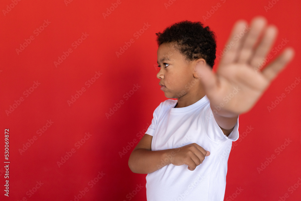 Portrait of resentful preteen boy making stop gesture. Mixed race child ...