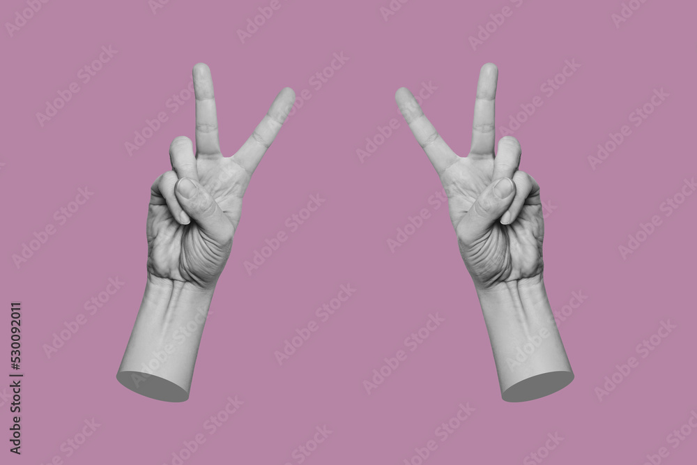 Two female hands showing a peace gesture isolated on a purple color ...
