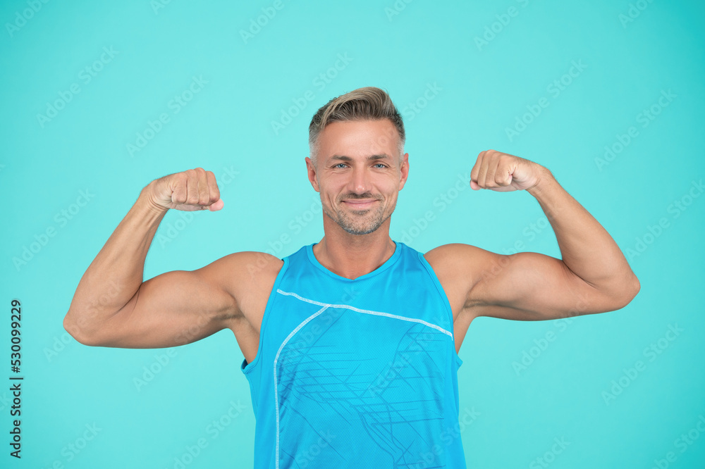 Happy muscular man blue background. Sportsman muscular arms showing ...