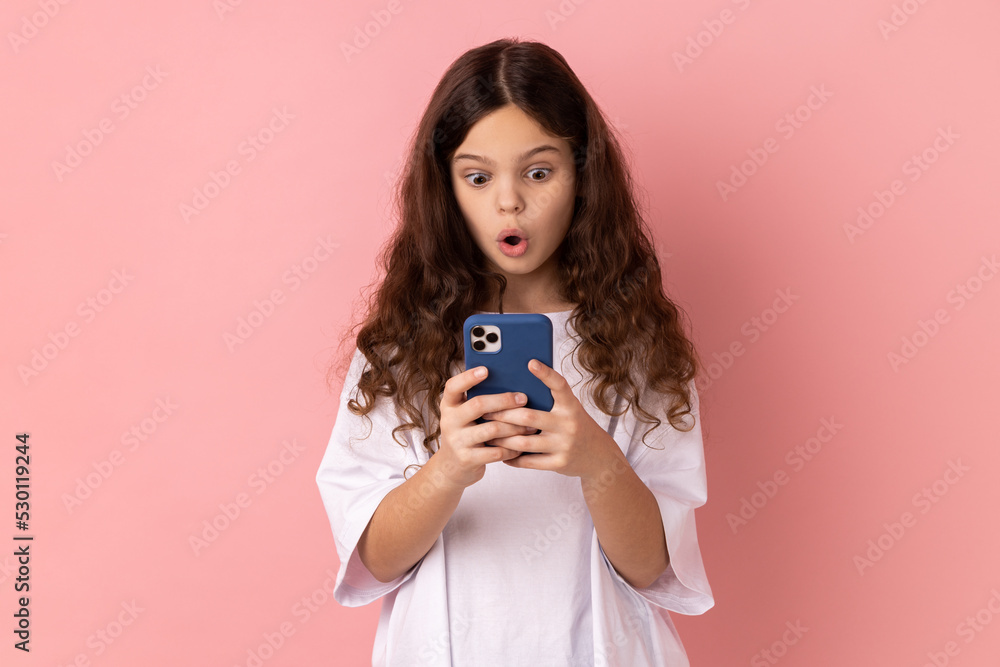 Mobile connection. Portrait of shocked astonished little girl wearing ...