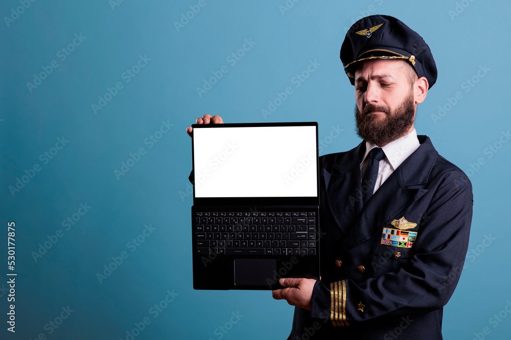 Serious airplane pilot showing laptop with empty white screen, aviation ...