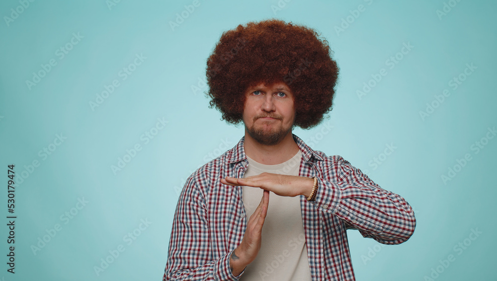Tired serious upset man 30s with lush hairstyle wig showing time out ...