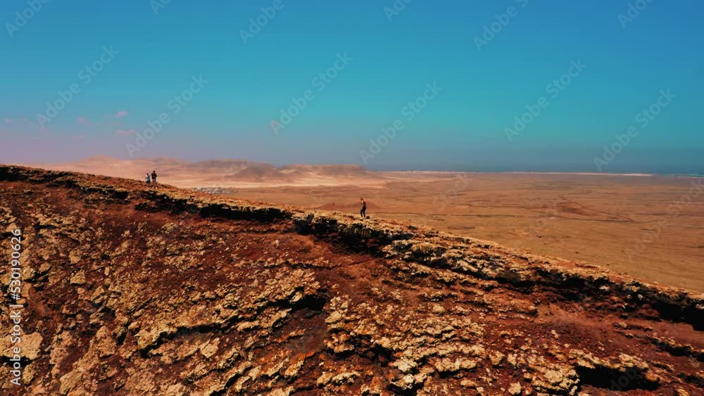 Unrecognizable tourists walk along edge of crater ridge. Spectacular ...