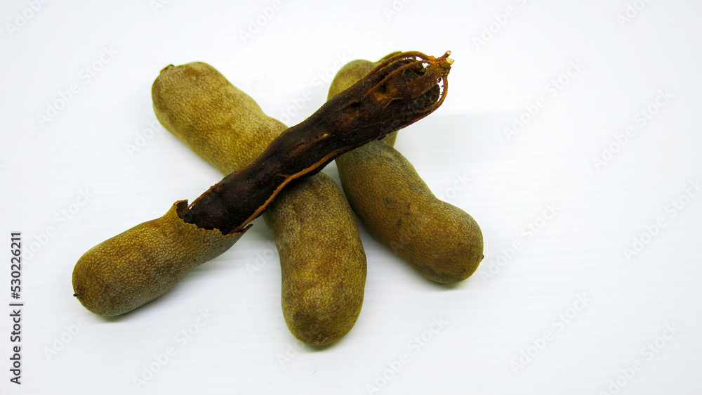 Fresh ripped tamarinds fruits on white background. One of the tamarind ...