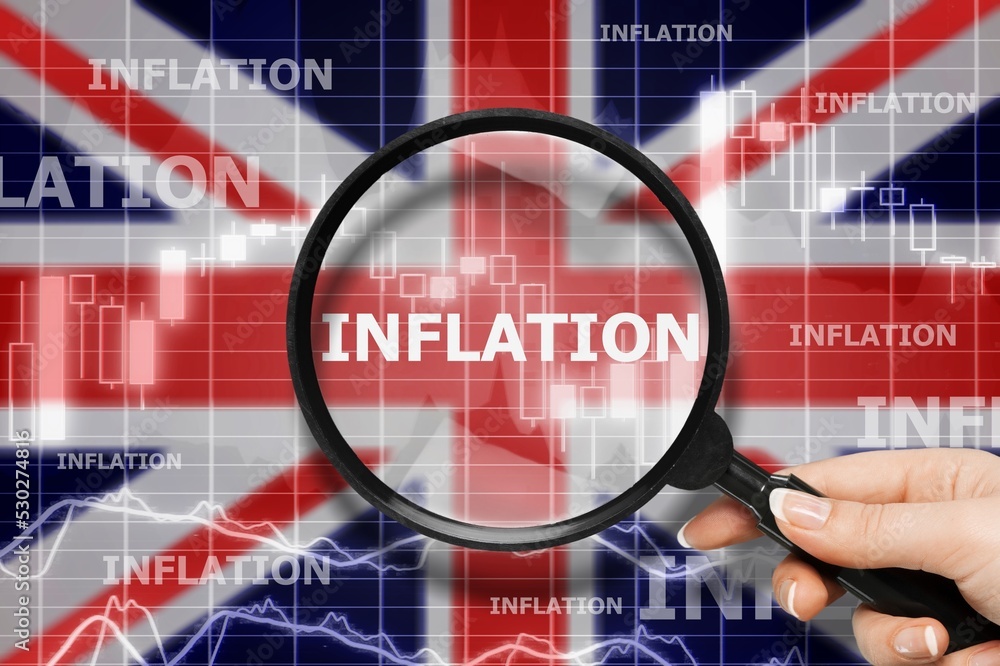 Magnifying glass focused on the word inflation on UK flag background ...